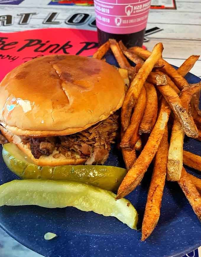A pulled pork sandwich so generously stuffed that the bun is doing its absolute best and barely keeping up.