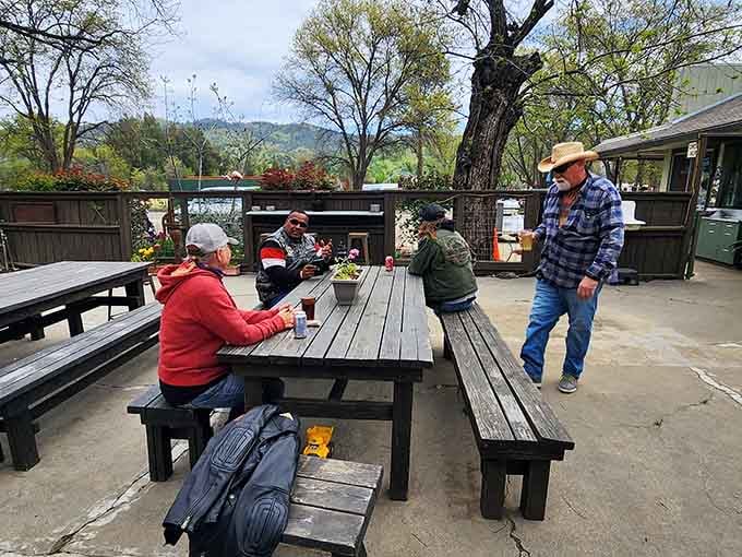 Outdoor picnic tables under the trees where locals gather, proving the best restaurants are community living rooms.