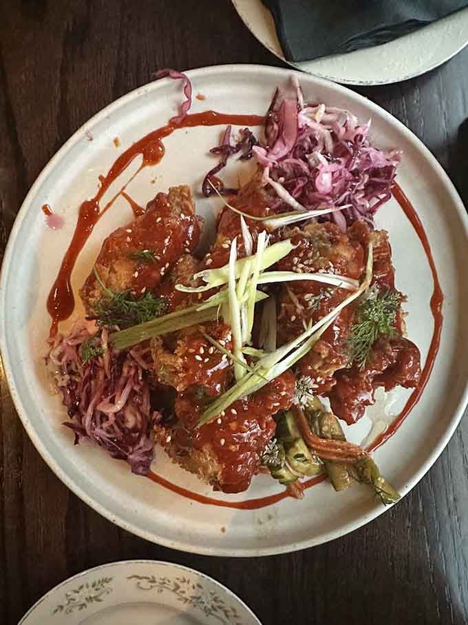 Crispy fried chicken draped in bold sauce, sitting next to pickled cabbage like two old friends who make each other better.
