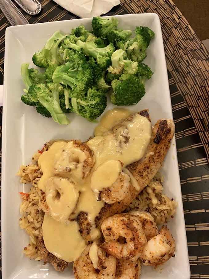 Seasoned fish and shrimp over rice, draped in a golden sauce, with bright broccoli keeping everything honest on the side.