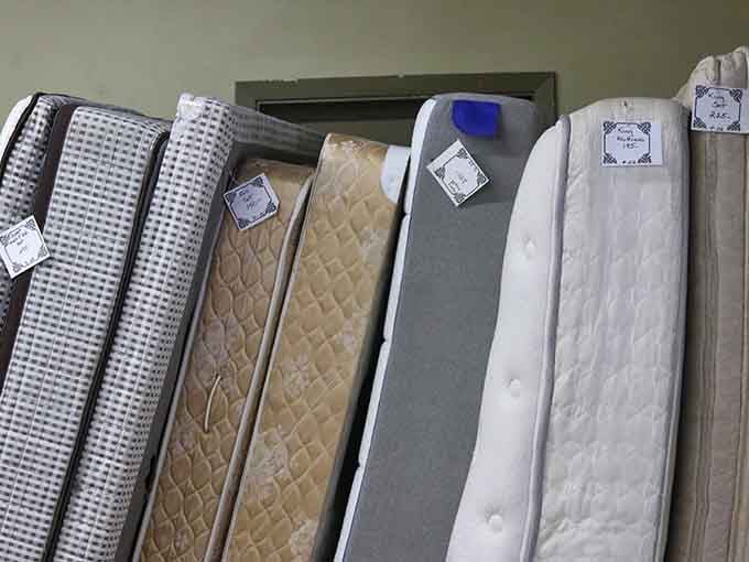 A lineup of mattresses standing at attention, each one tagged and ready to give someone a genuinely good night's sleep.
