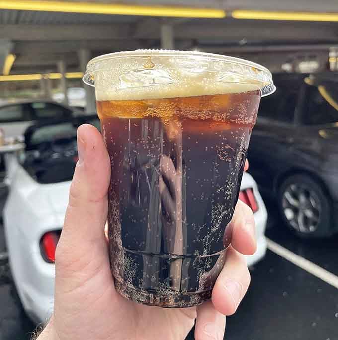 Bubbling, ice-cold root beer with a frothy foam crown, held up like a trophy, because it absolutely deserves one.