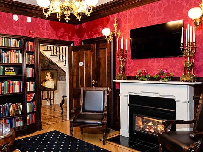 Rich red walls, candelabras, a crackling fireplace, and bookshelves. This library room is pure, unapologetic old-world elegance.