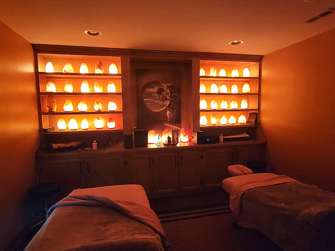 Two massage tables, warm amber light, and rows of glowing salt lamps make this room feel like pure serenity.