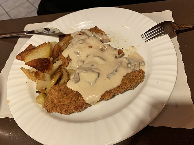 Breaded schnitzel blanketed in creamy mushroom gravy with golden fried potatoes, simple ingredients treated with genuine care and real skill.