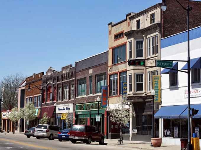Beloit's downtown intersection glows under a brilliant blue sky, with brick-paved crosswalks and a mix of buildings that tell a rich city story.