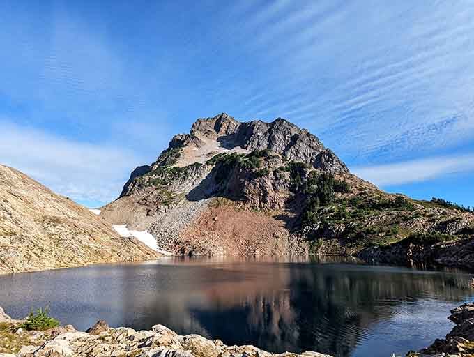That perfectly still alpine lake mirrors a rugged peak so crisply, you'll question which direction is actually up.