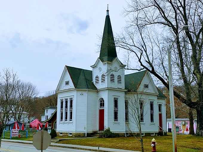 A bright white church with red doors and a sharp steeple &mdash; Ohiopyle's little chapel stands calm against the bare winter trees.