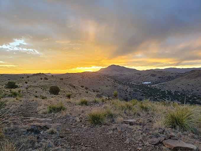 Mountain silhouettes frame a dramatic sunset where clouds catch fire, proving nature's light show beats any theater production easily.