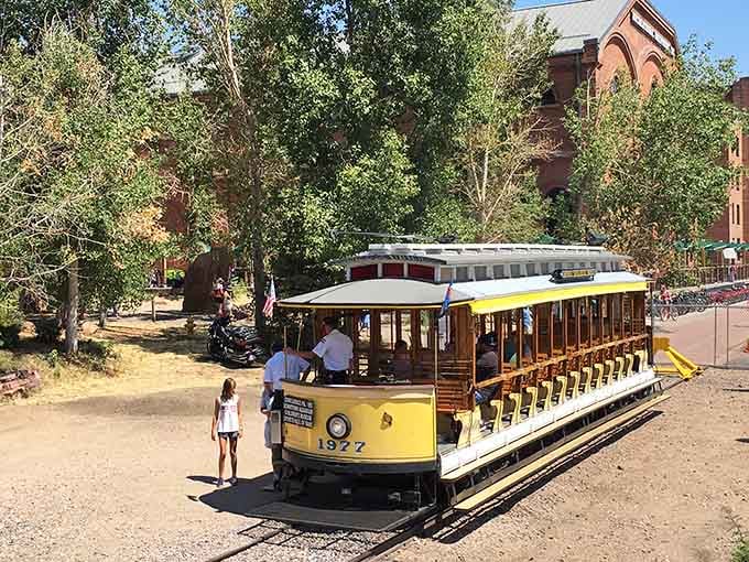 Dappled summer light catches the yellow Denver Trolley perfectly, with that handsome brick building keeping watch from behind the trees.