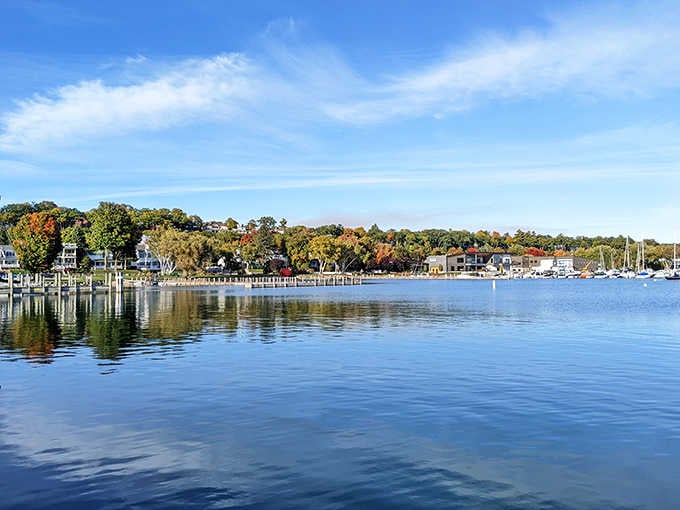 Lake Charlevoix mirrors the fall foliage in a reflection so still and clear it looks like nature showing off on purpose.