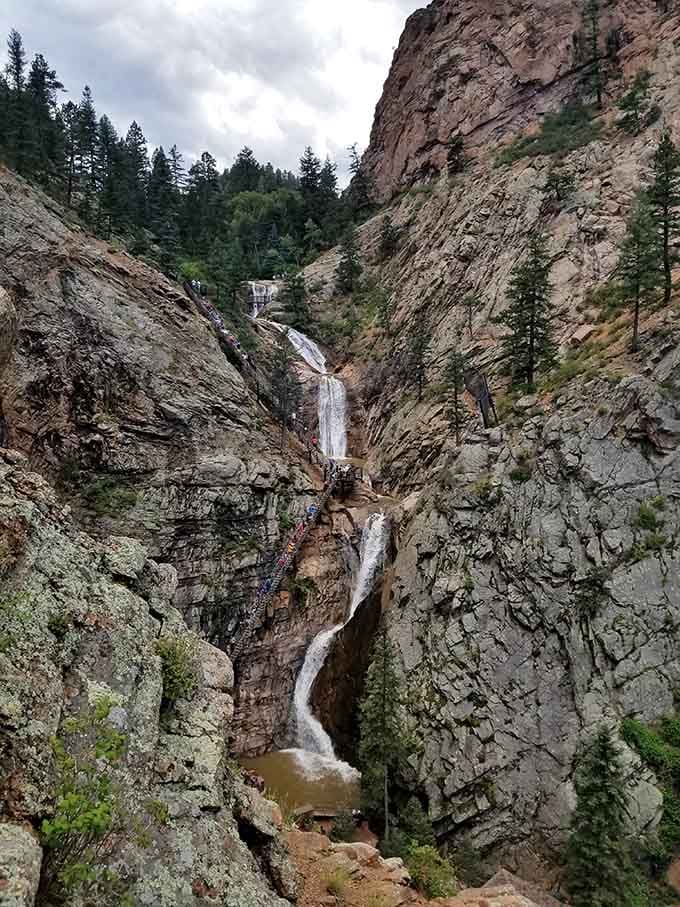 Crystal-clear water pools at the base of Whitmore Falls, catching the Colorado sunshine like a natural mirror set into the red earth.